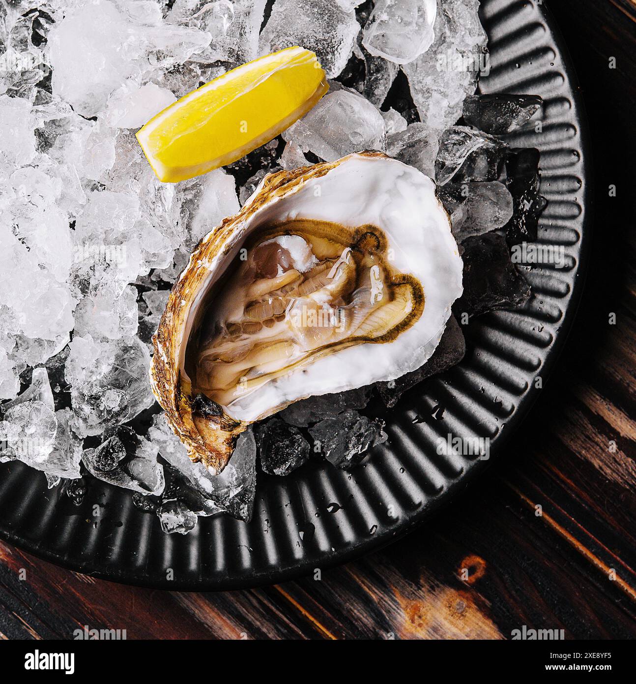 Fresh raw open oyster with ice and lemon slices Stock Photo - Alamy