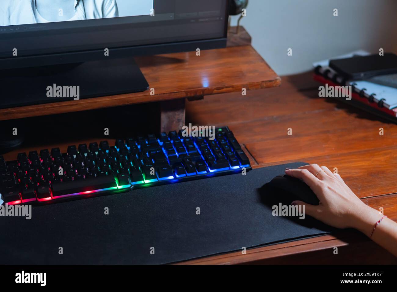 A person using a computer with a colorful backlit keyboard and a mouse ...