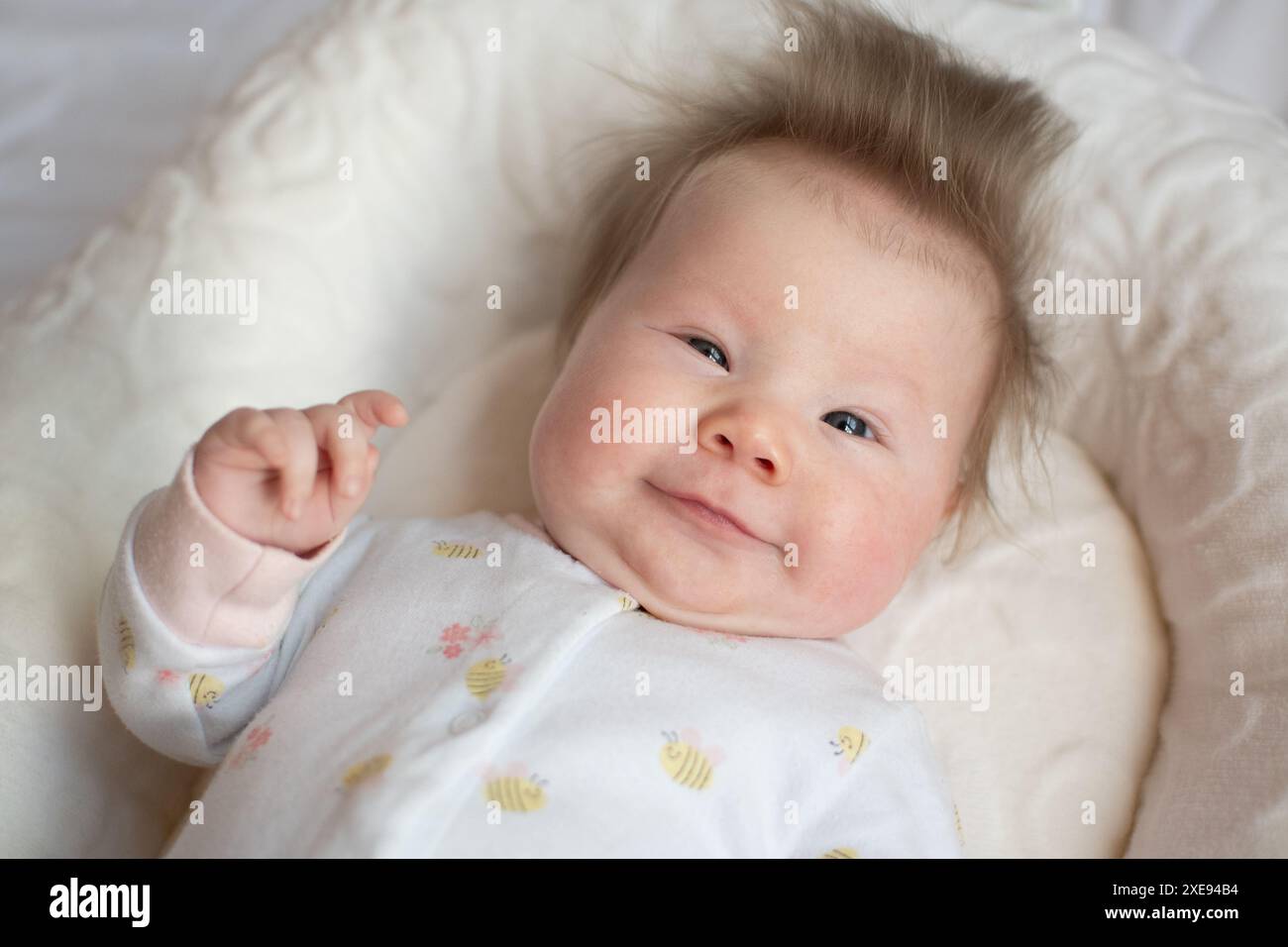 Cute smiling baby. 3 month old newborn baby girl in a baby lounger ...