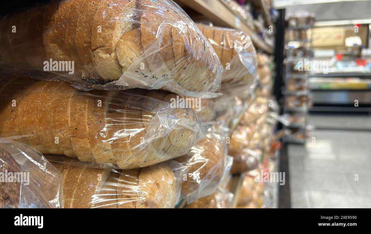 A close-up view of packaged loaves of bread stacked on a shelf in a ...