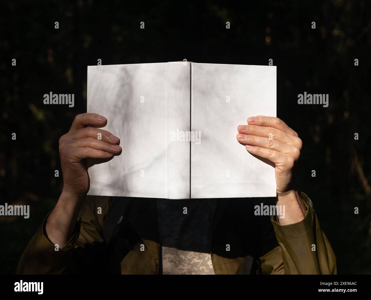 . Hand holding white blank open book cover mockup in nature, sunny day ...