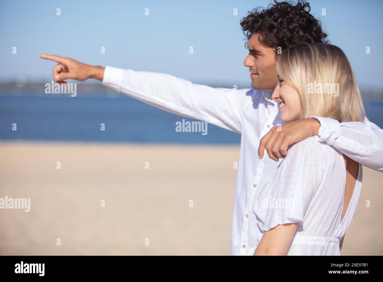 loving couple on the beach pointing into the distance Stock Photo - Alamy