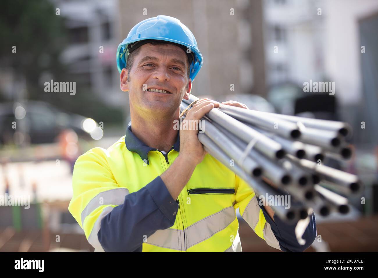 worker carrying pipes on his shoulder on construction site Stock Photo ...