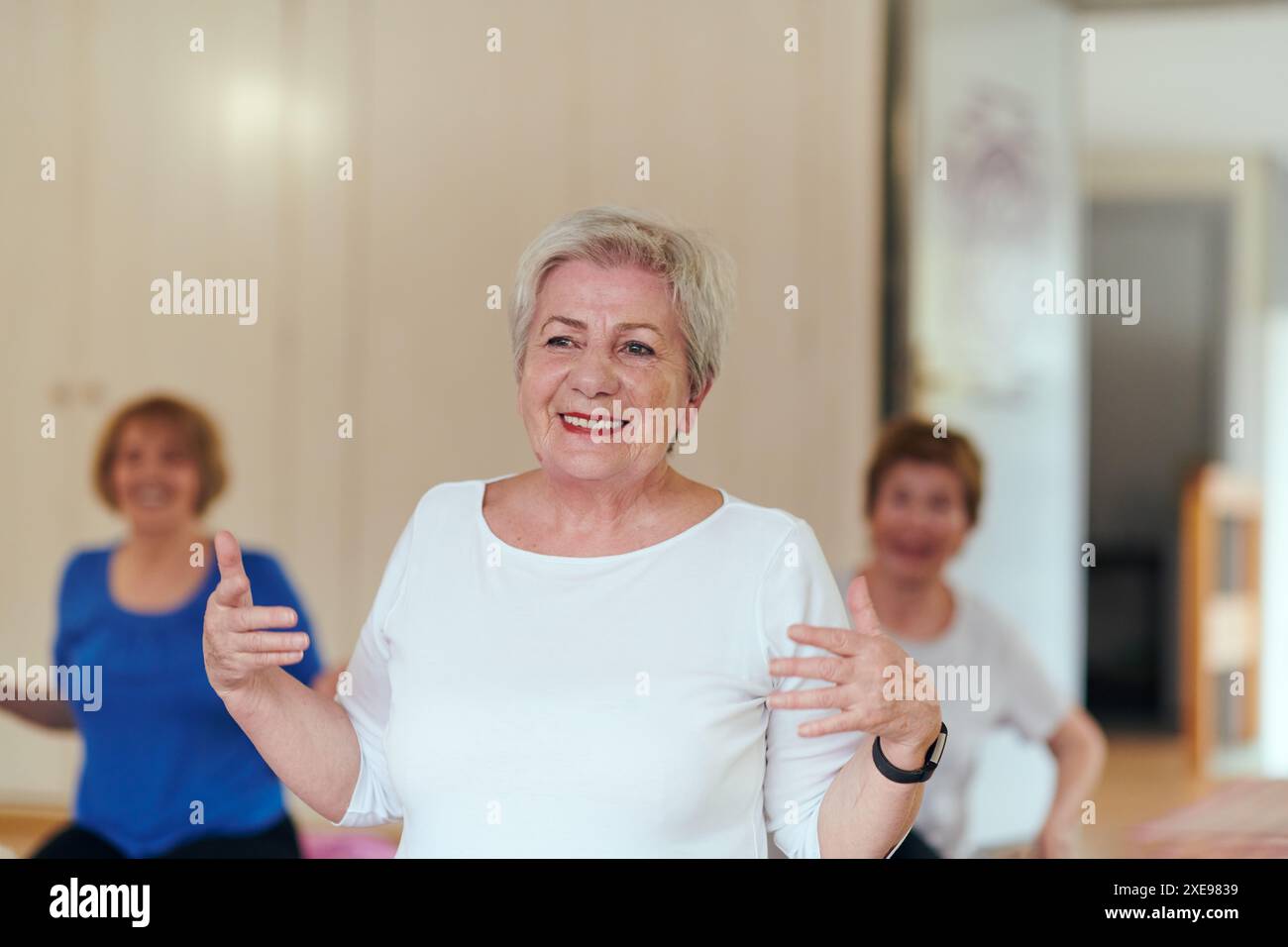 A group of senior women engage in various yoga exercises, including ...