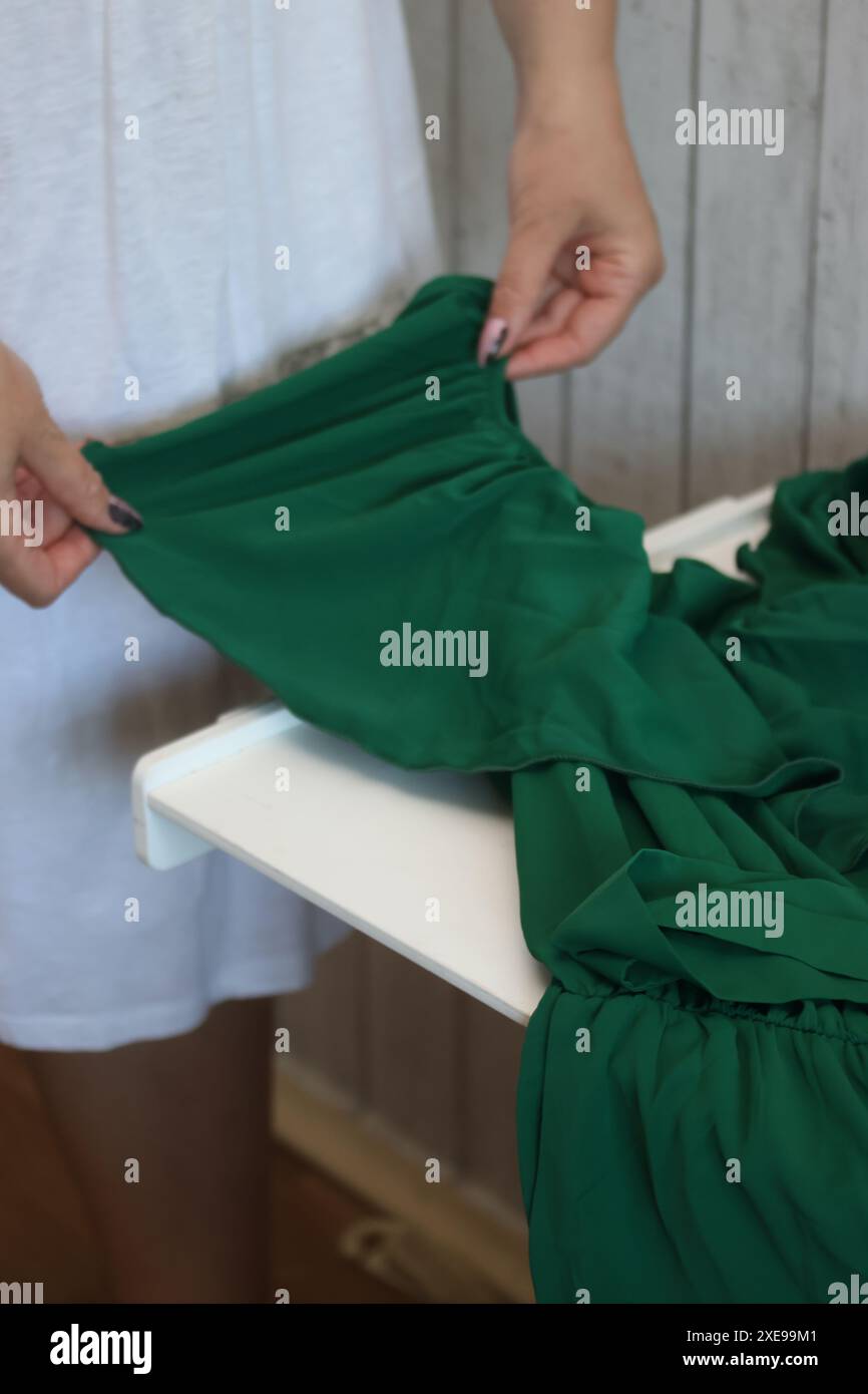 The woman makes a review of the summer dress of green. Lays it on the ...