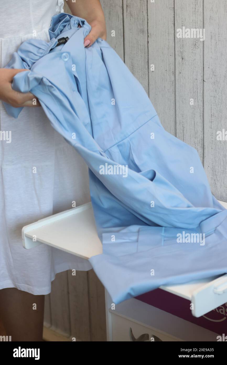 The woman makes a review of the summer dress of blue. Lays it on the ...