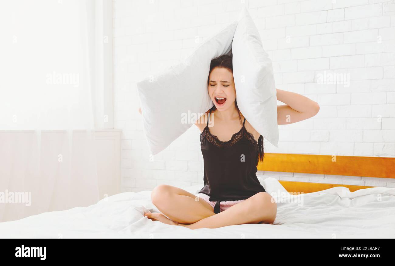 Young Woman Clutching a Pillow Over Her Head Stock Photo - Alamy