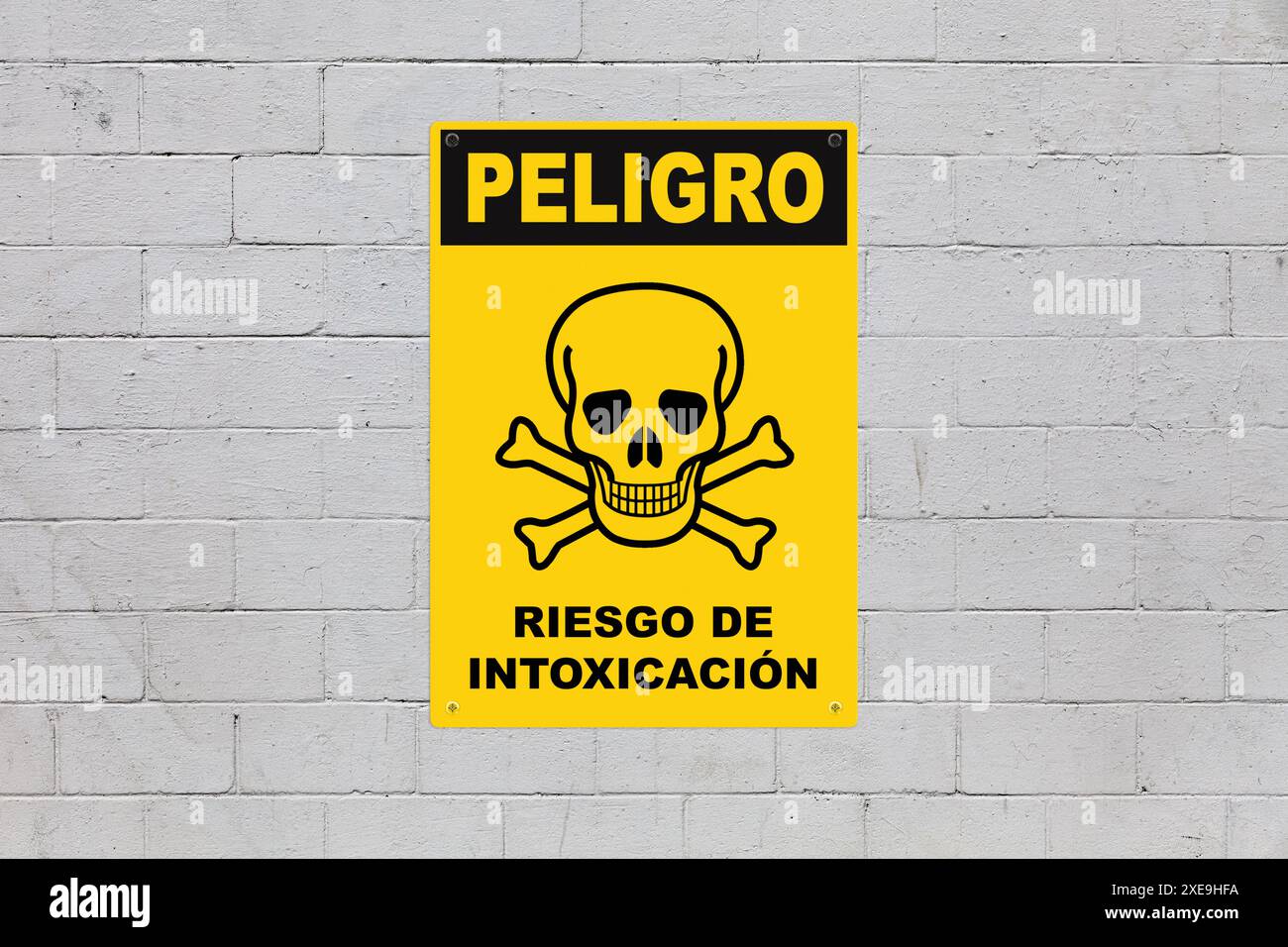 Yellow warning sign screwed to a brick wall to warn about a threat. In ...