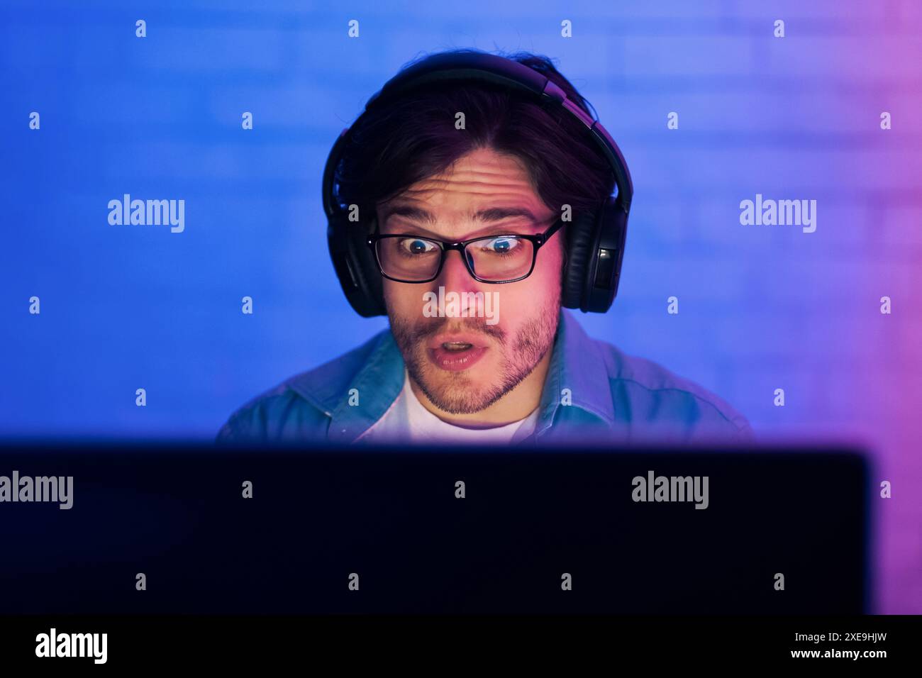 Shocked Gamer Wearing Headphones While Gaming at Night Stock Photo - Alamy
