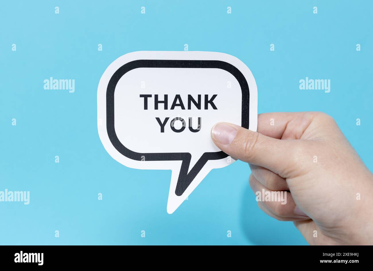 Hand holding a speech bubble with message Thank You isolated on blue ...