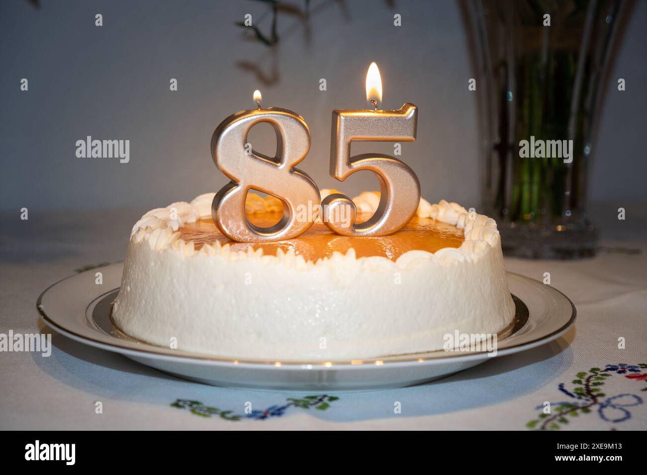 An adult hand lights birthday candles with the number 85 on a nice ...