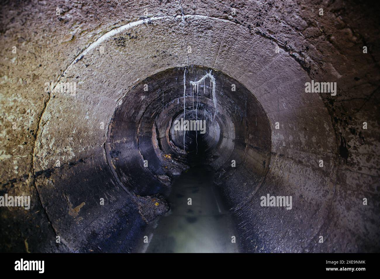 Inside underground urban sewer system. Sewage flowing in round sewer ...