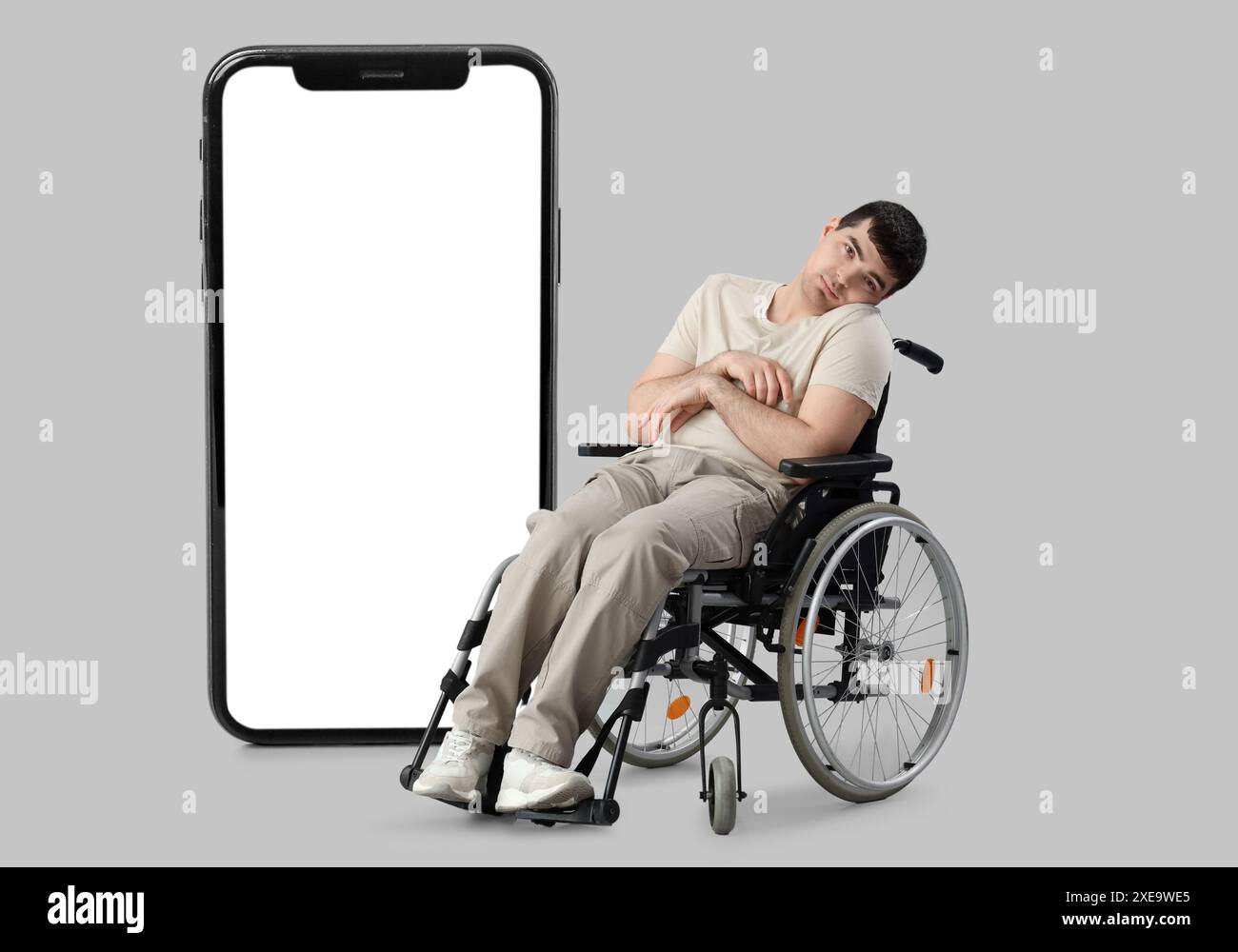 Big mobile phone and young man suffering from cerebral palsy on grey ...