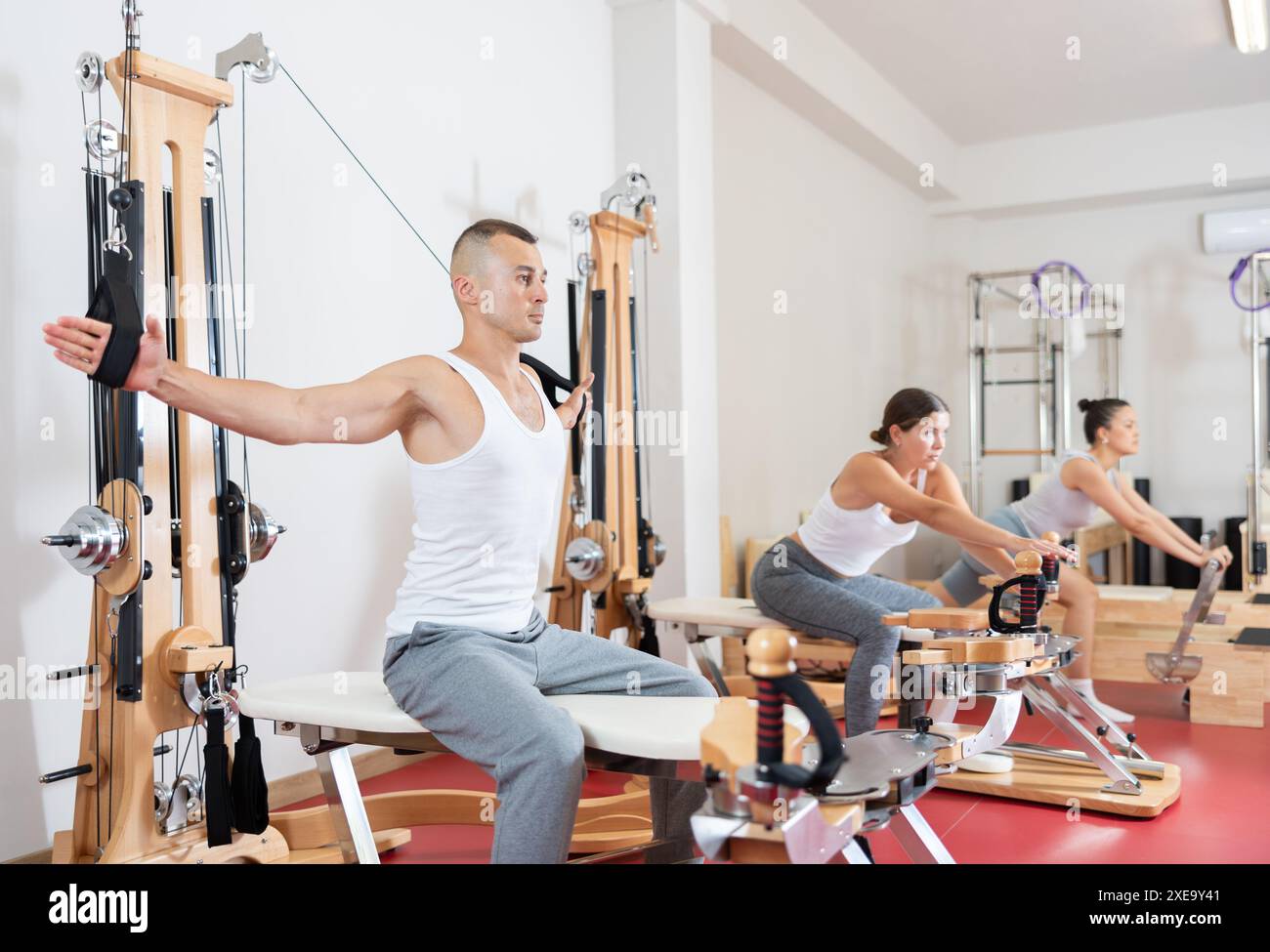 Sportive young guy training her arms pulling handle of cable exercise ...