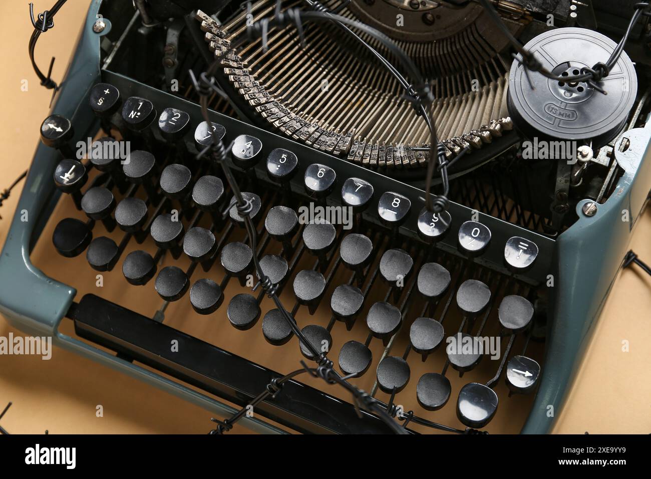 Vintage typewriter with barbed wire on beige background. Printing ban ...