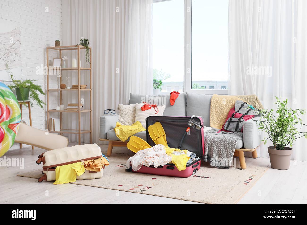 Interior of messy living room with sofa, scattered things and suitcases ...