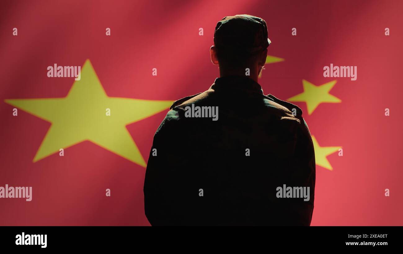 Member of chinese army doing saluting hand gesture towards China flag ...