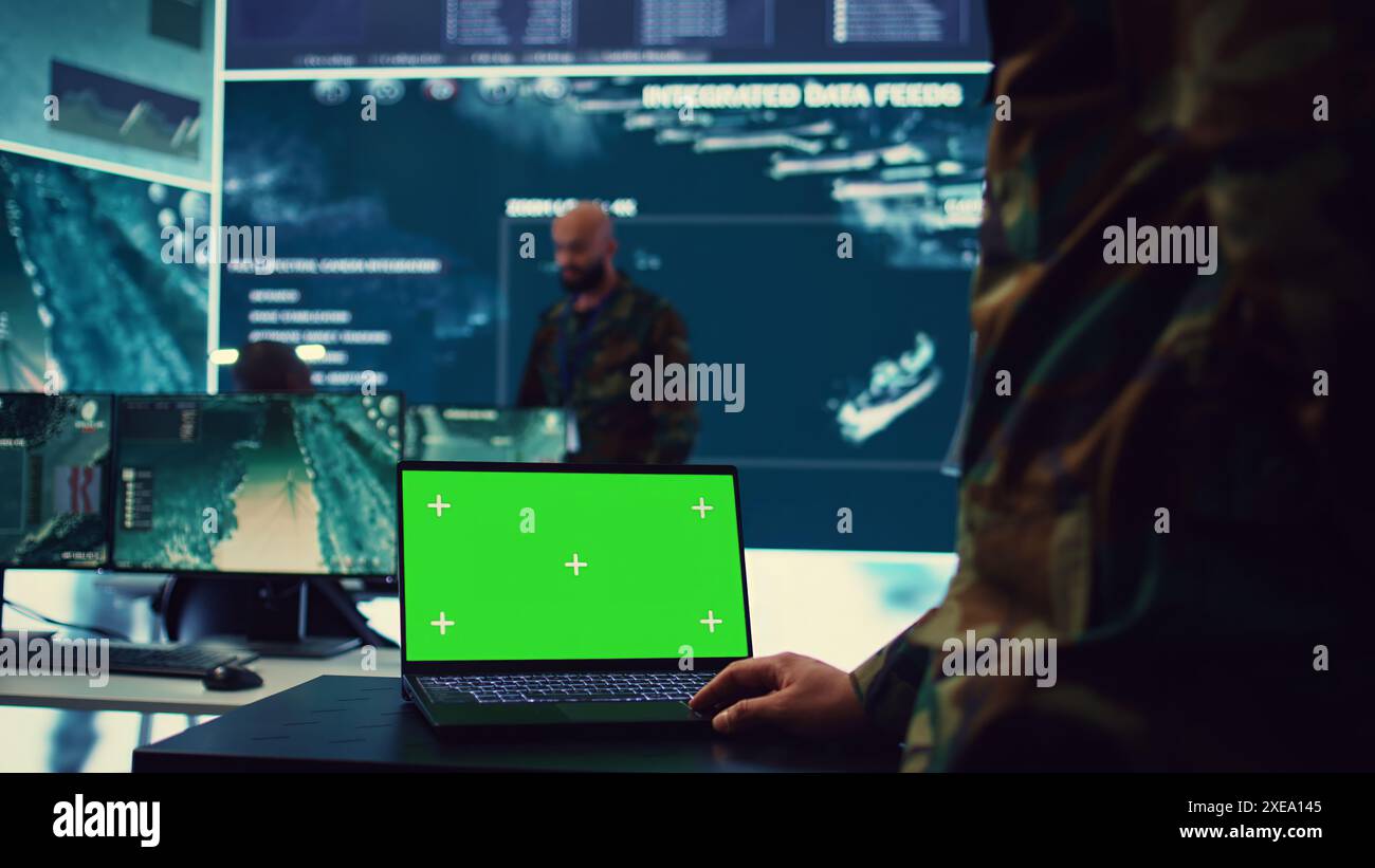 Army officer studies isolated greenscreen display on a laptop in ...