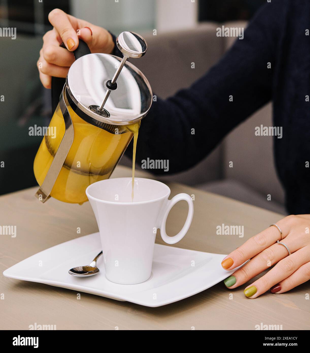 A woman pours sea buckthorn tea from a teapot into a mug Stock Photo ...