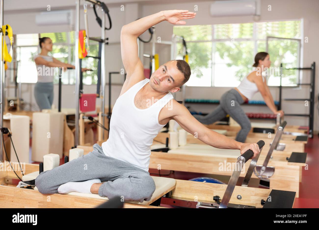 Active young man doing arm exercises on reformer device Stock Photo - Alamy