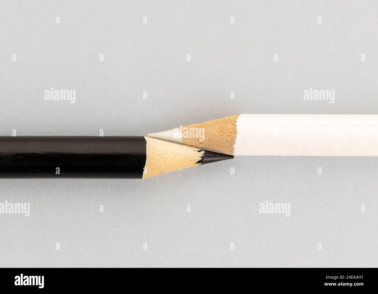 Black pencil and white pencil touching together on gray background ...