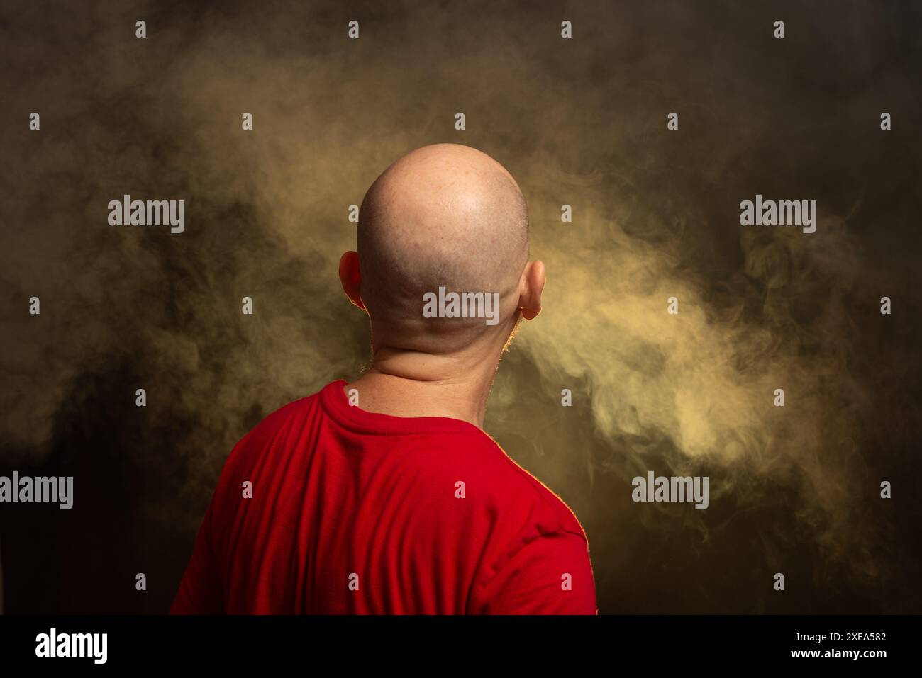 Bald bearded man wearing red shirt with his back to the camera. Studio ...