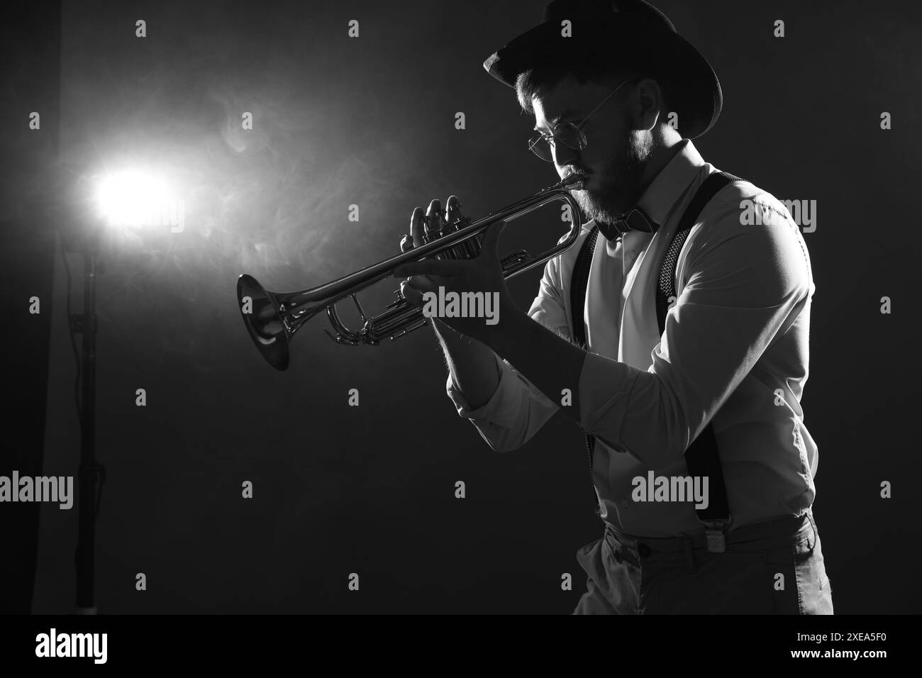 Professional musician playing trumpet on dark background with smoke ...