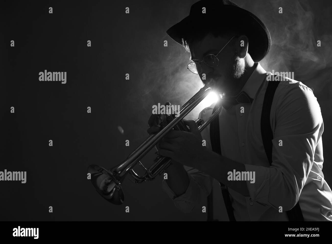 Professional musician playing trumpet on dark background with smoke ...