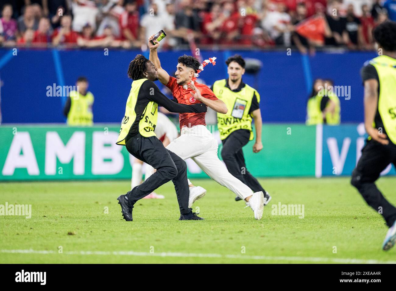 Hamburg, Germany. 26th June, 2024. A pitch invader is stopped by security during the UEFA Euro ...