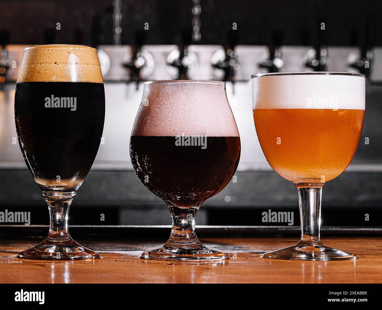 Different types of craft beer in glasses on table in pub interior in ...