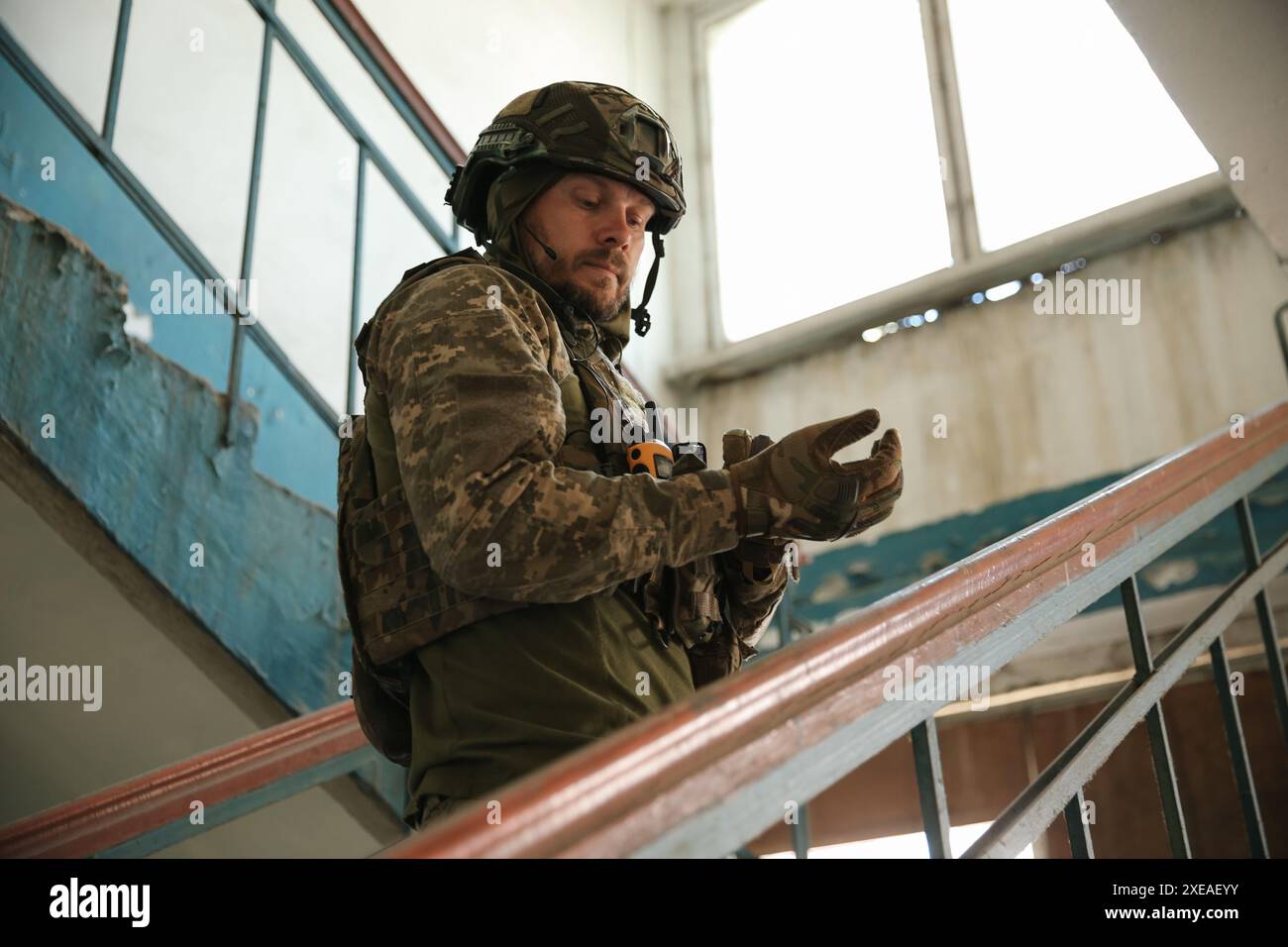 Military mission. Soldier in uniform on stairs inside abandoned ...