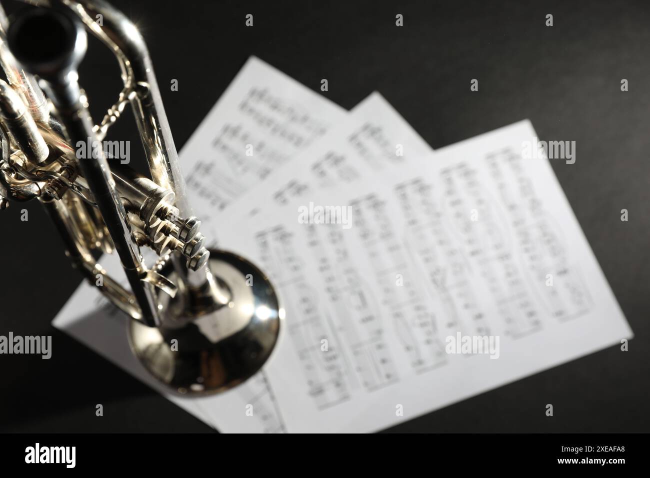 Closeup view of shiny trumpet and music sheets on dark background ...