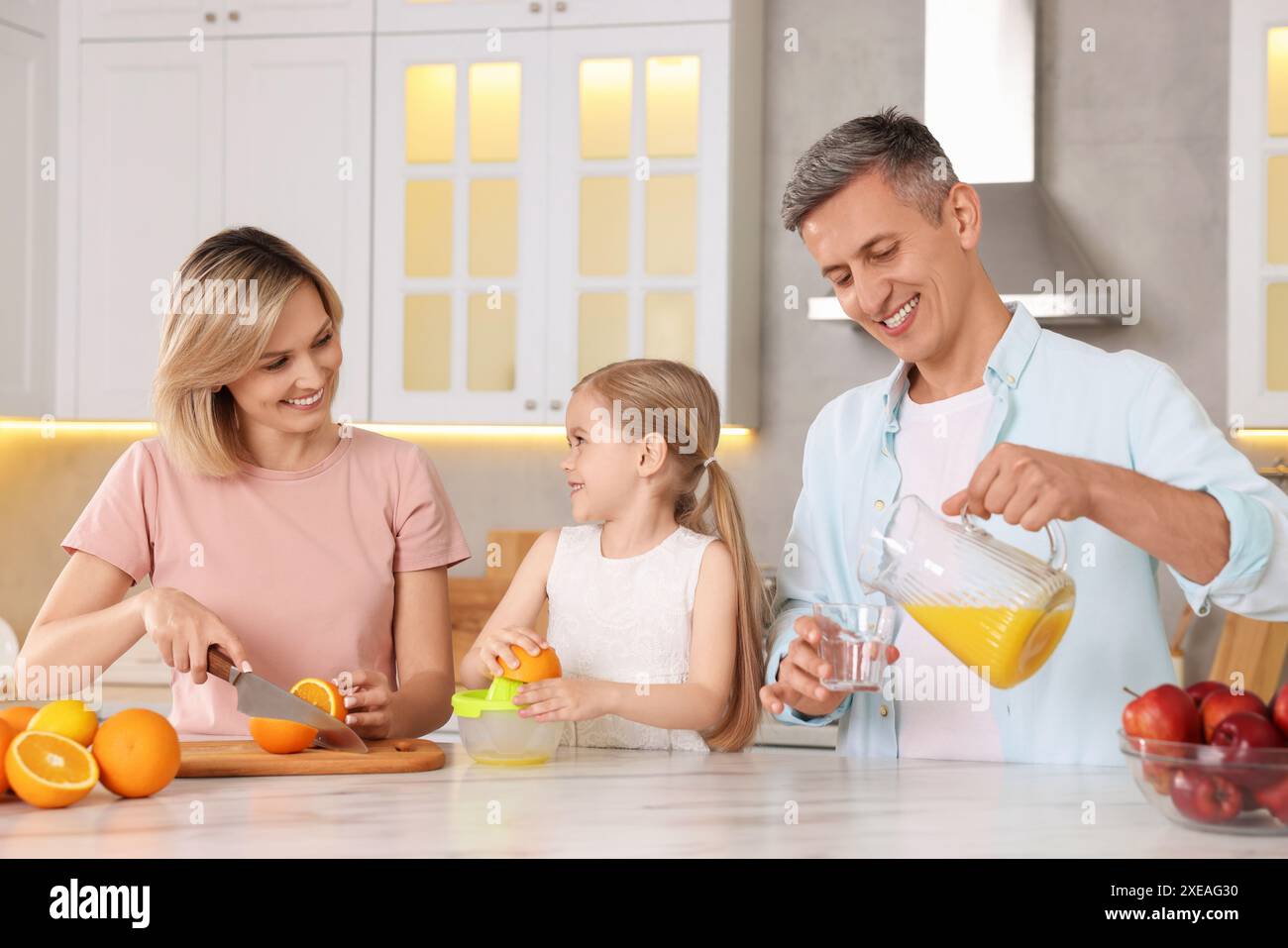 Happy family making juice at white marble table in kitchen Stock Photo ...