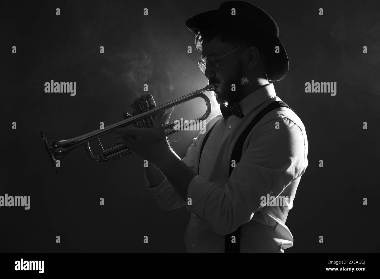 Professional musician playing trumpet on dark background with smoke ...