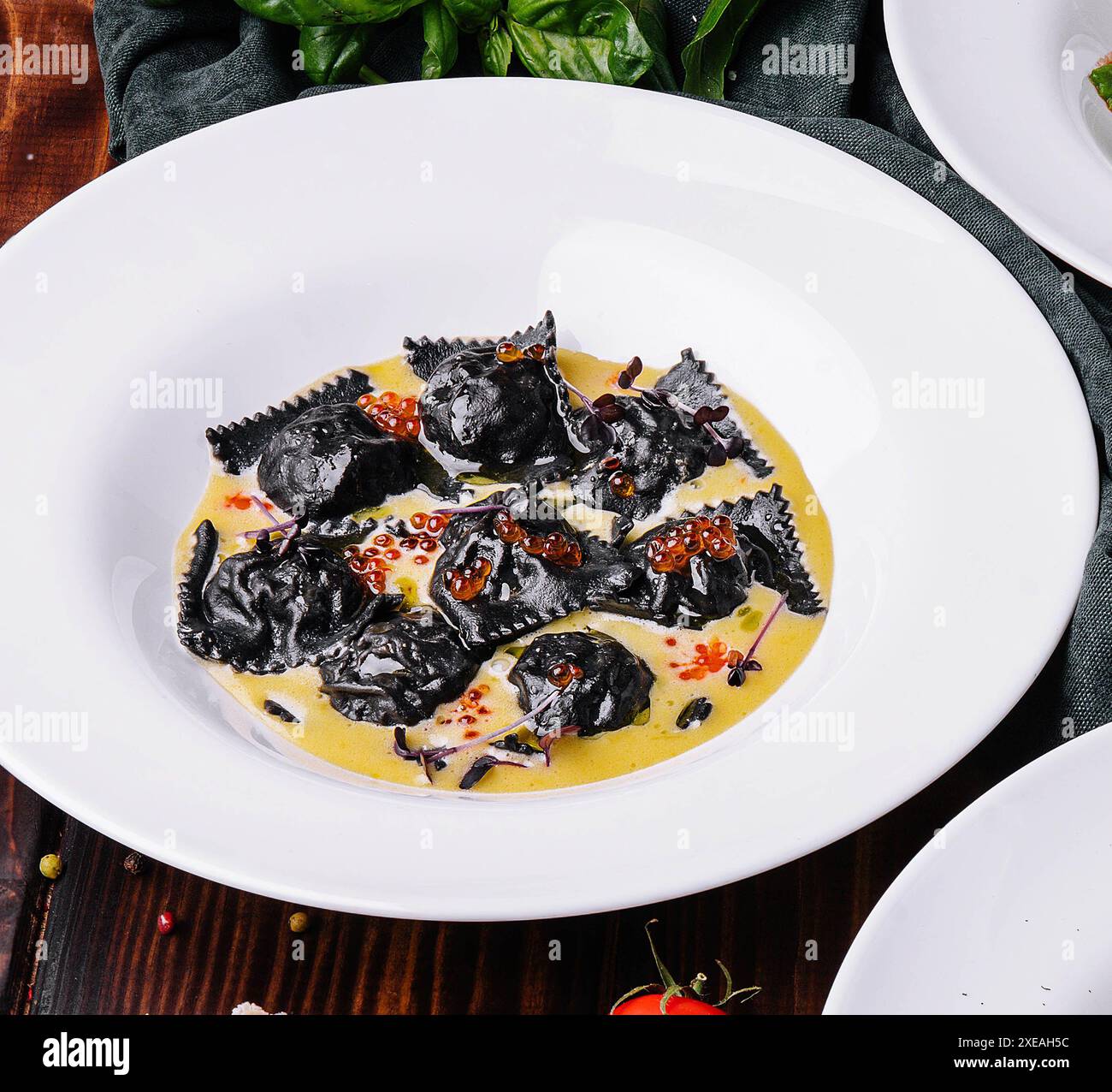 Black ravioli with red caviar in white plate Stock Photo - Alamy