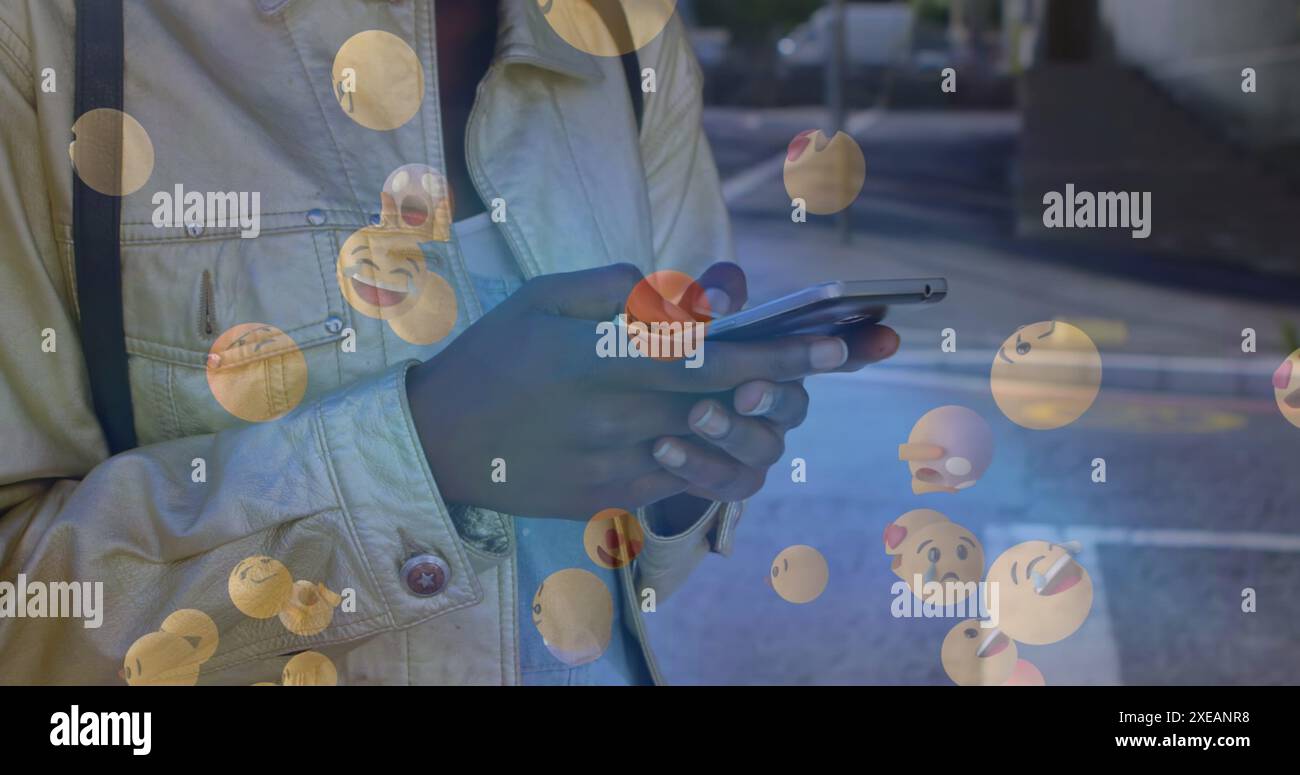 Image of falling emoji over african american woman using smartphone ...