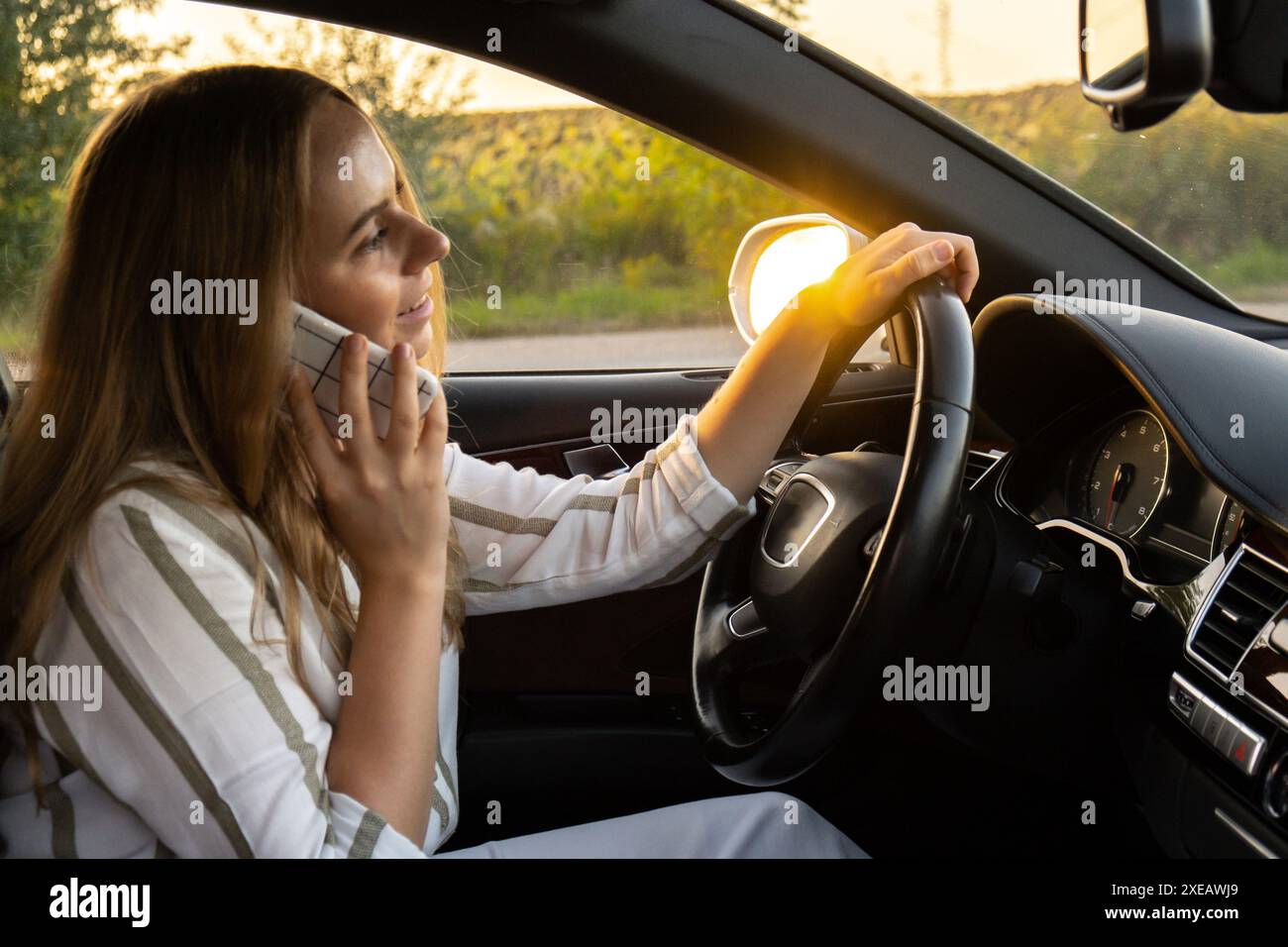 Happy young woman speaking by mobile phone while driving car. Business ...