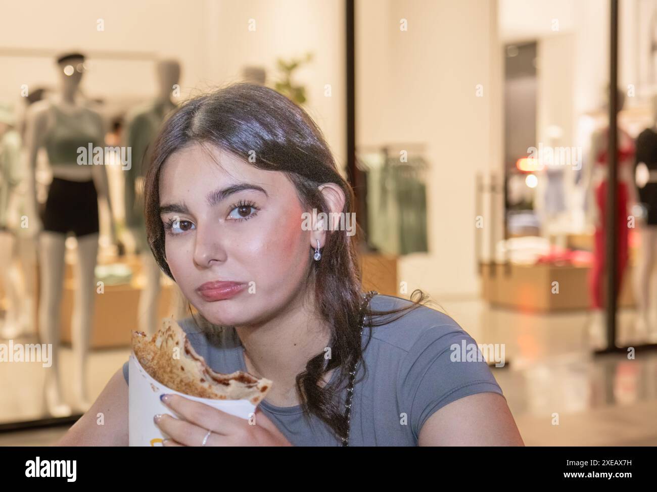 The young model eating a dessert on a rainy afternoon on a bench in the ...