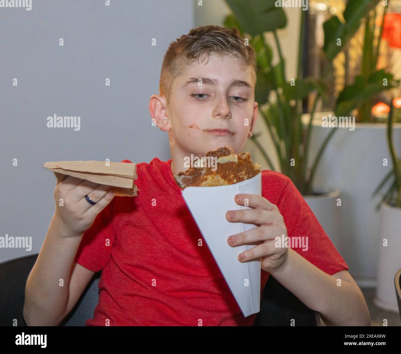 Child model eating a dessert on a rainy afternoon on a bench in the ...