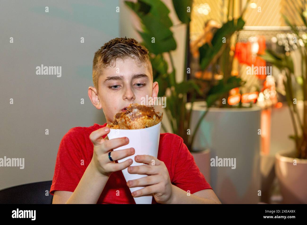 Child model eating a dessert on a rainy afternoon on a bench in the ...