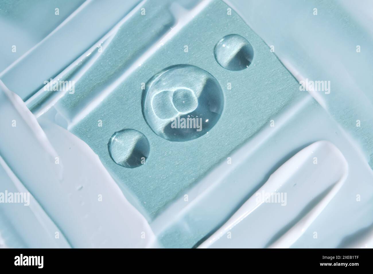A smear with drops of serum on a blue background Stock Photo - Alamy