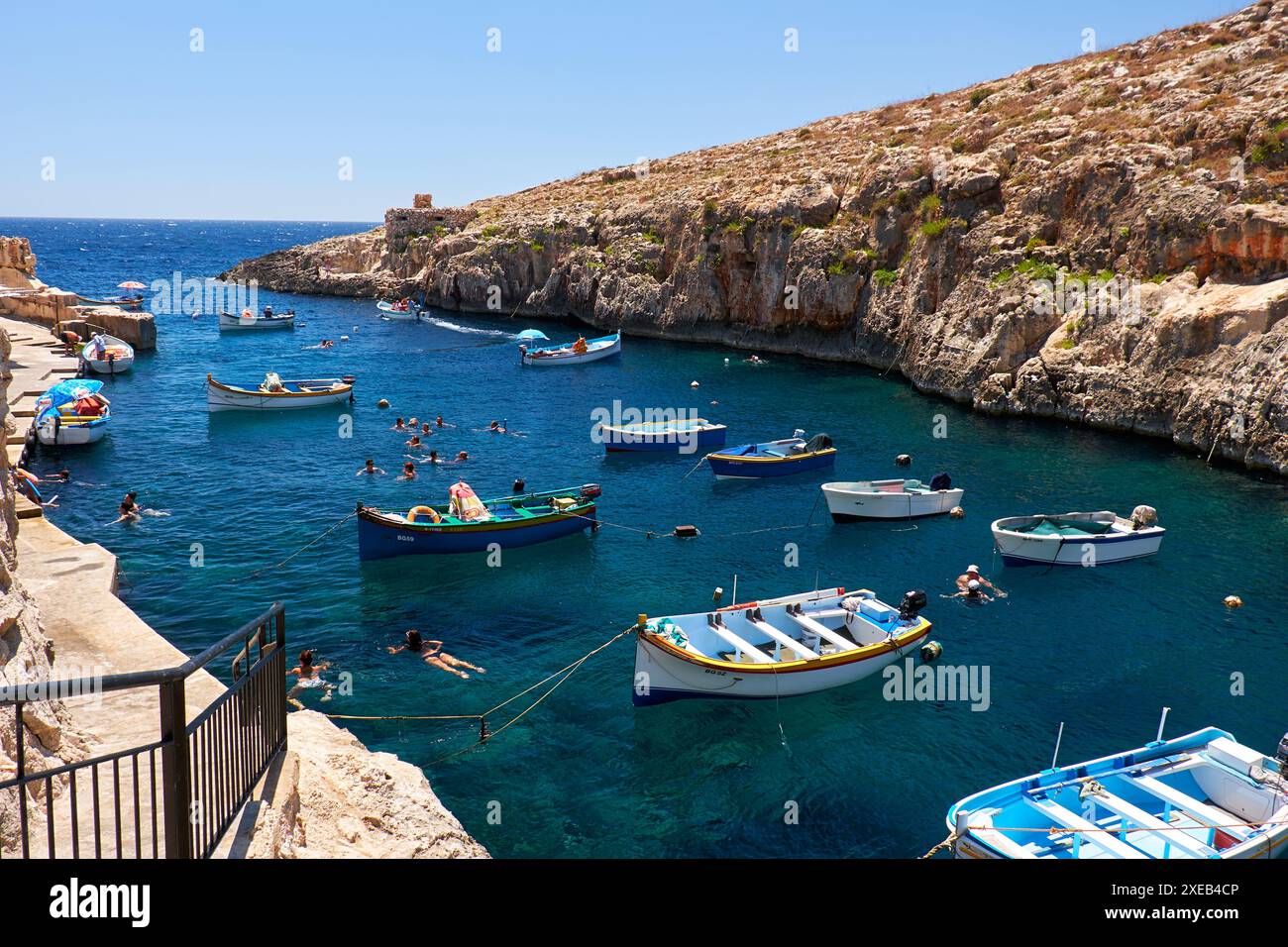 Maltese boats and swimming people in water of Wied Zurrieq Fjord on ...