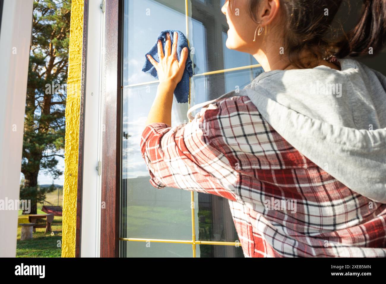 Woman manually washes the window of the house with a rag with spray ...