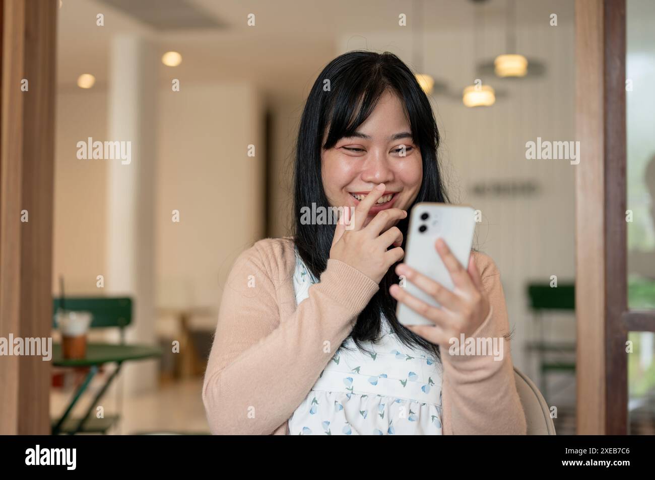 A cheerful Asian woman is laughing while reading messages on her ...