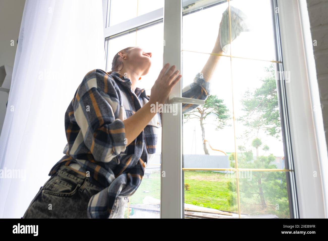 Woman manually washes the window of the house with a rag with spray ...