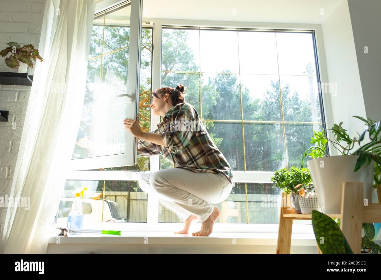 Woman manually washes the window of the house with a rag with spray ...