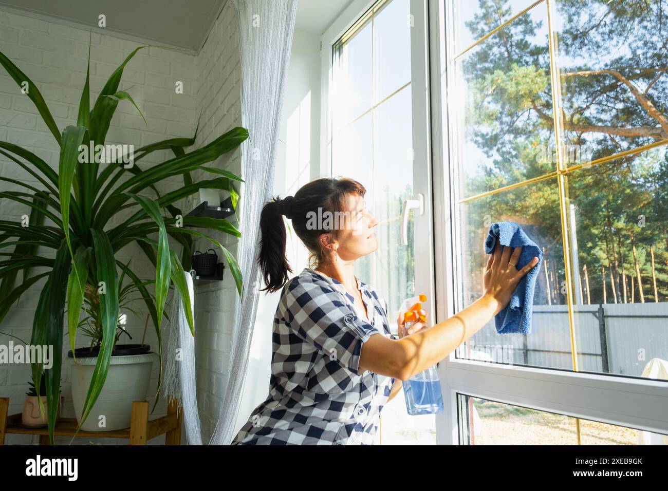 Woman manually washes the window of the house with a rag with spray ...