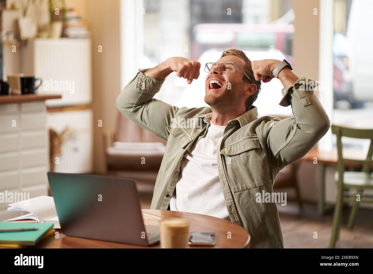 Portrait of pleased, smiling young man shouting with rejoice, sitting ...