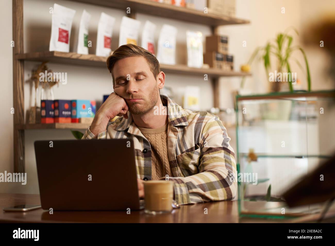 Portrait of bored freelancer, digital nomad sitting with laptop in cafe ...
