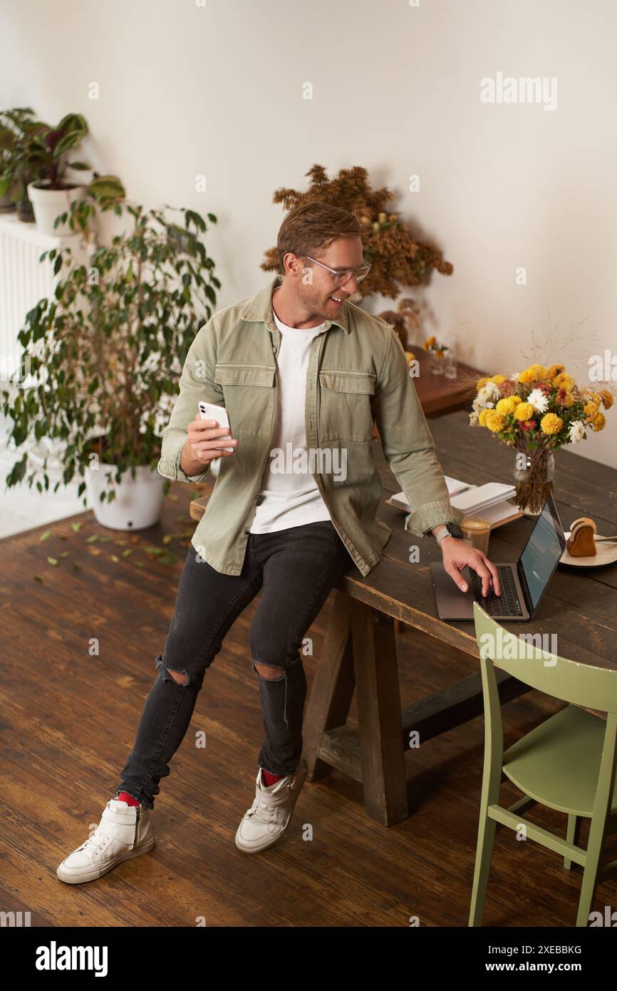 Portrait of young happy man, businessman in office, leaning on table ...